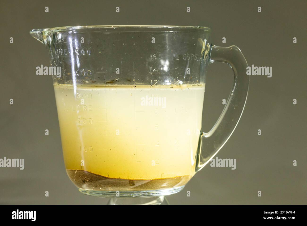 Sand in a jug of water with the coarse particles settled on the bottom ...
