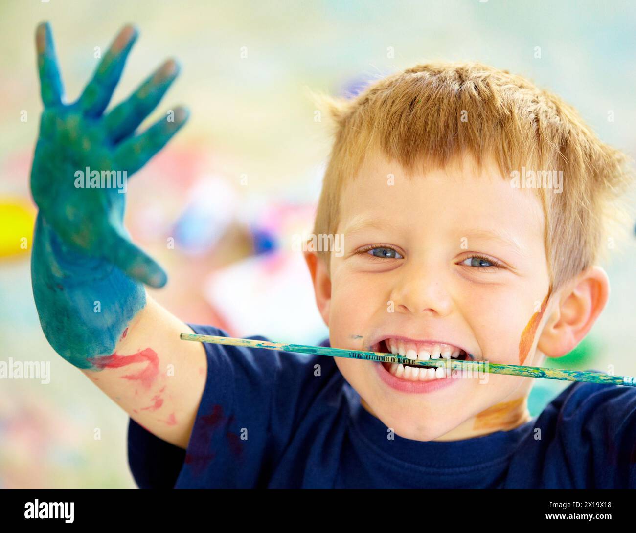 Boy, paint and mess or playing portrait, happy child in preschool or ...