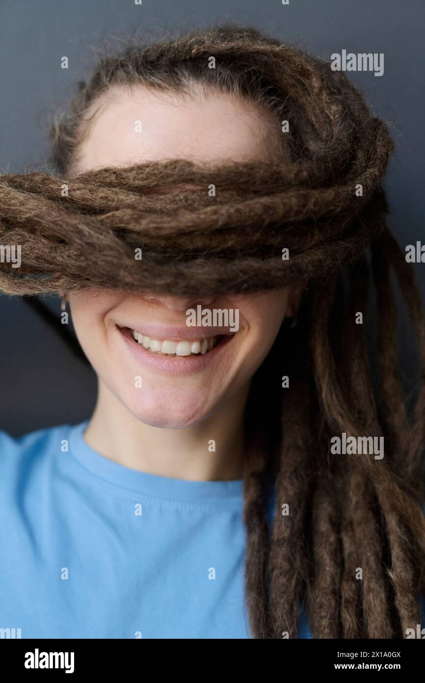 Vertical closeup of smiling Caucasian woman with long dreadlocks style ...