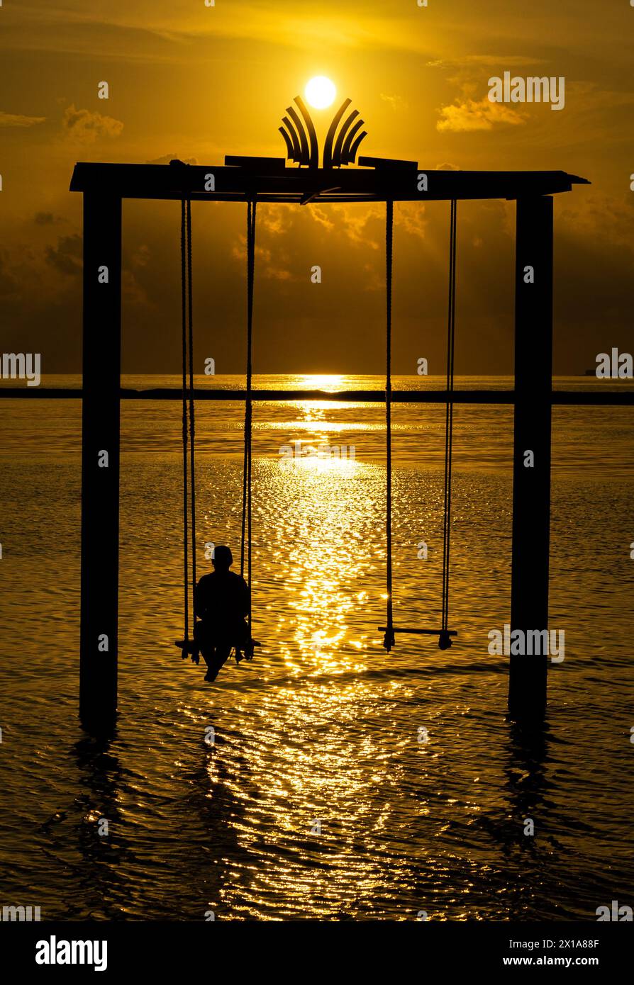Women watching a sunset on a overwater swing in the Maldives Stock ...