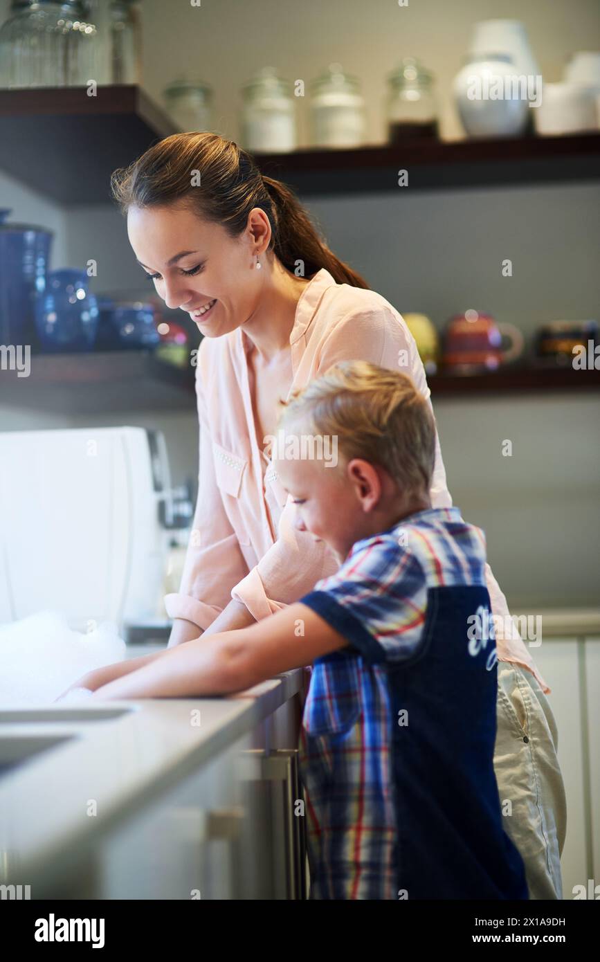 Happy, mother and child in kitchen cleaning for education, development ...