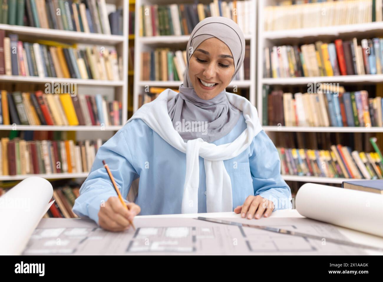 A cheerful Muslim woman architect drawing and reviewing building plans ...