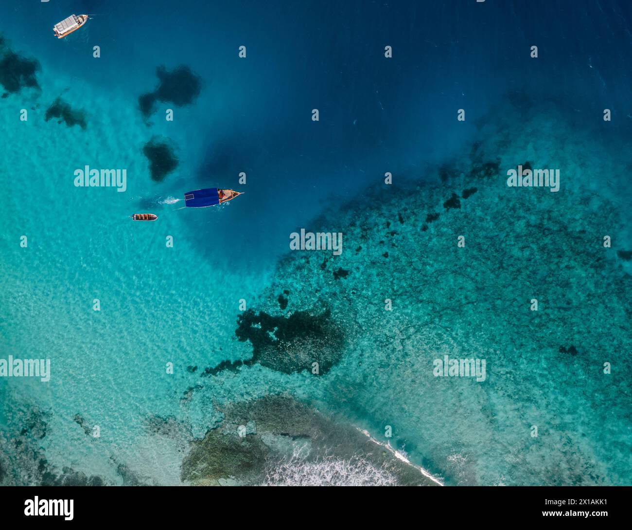 A boat towing a wooden boat behind over the beautiful blue Indian Ocean ...