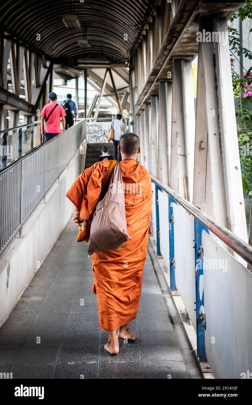 A Buddhist monk walking along a sky walk towards the Sala Daeng BTS ...