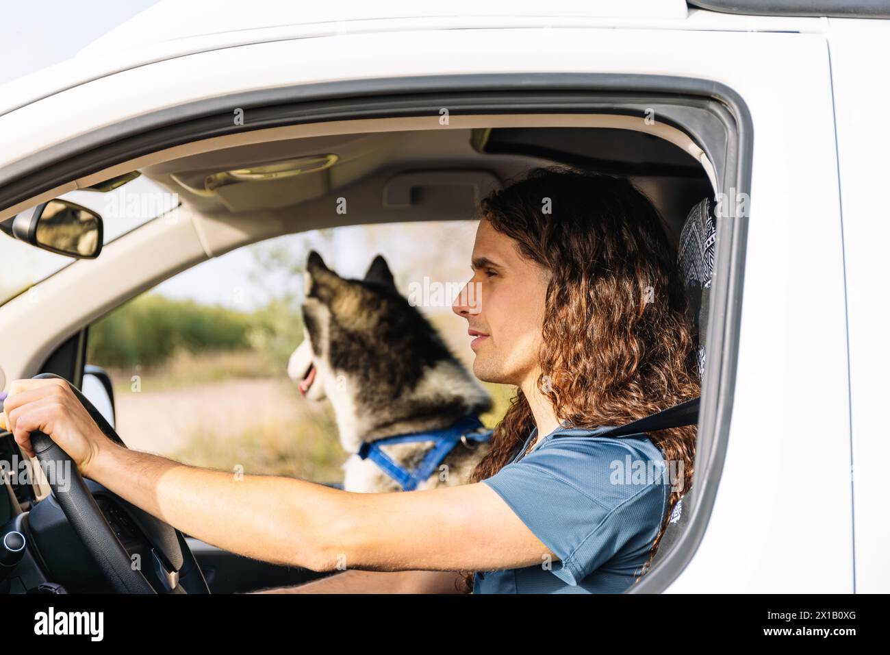 Horizontal photo young man with long curly hair focusing on the road as ...