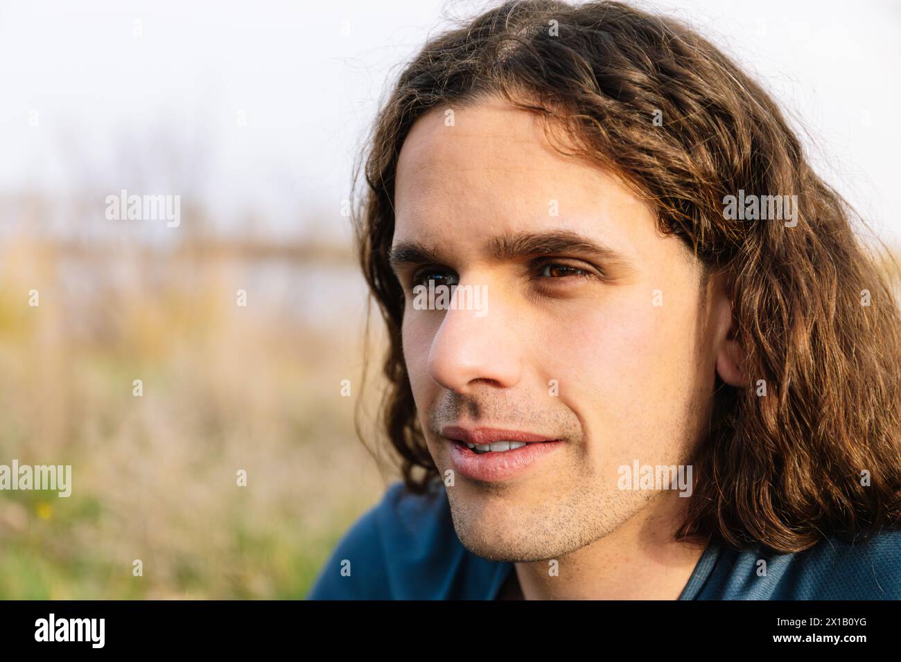 Horizontal photo a close-up portrait of a young man with long, curly ...