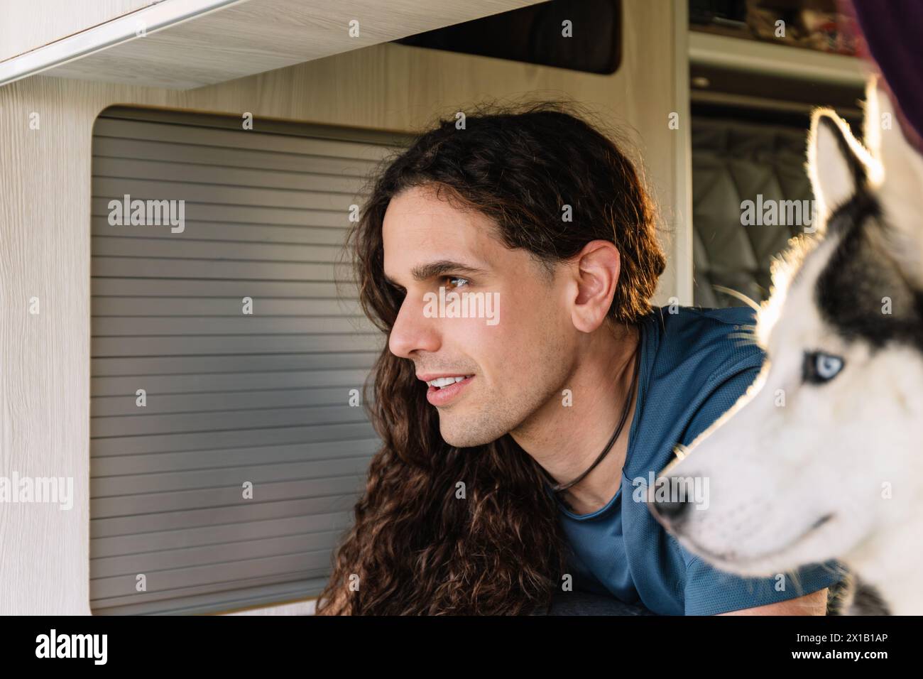 Horizontal photo a smiling man with curly hair and his attentive husky ...
