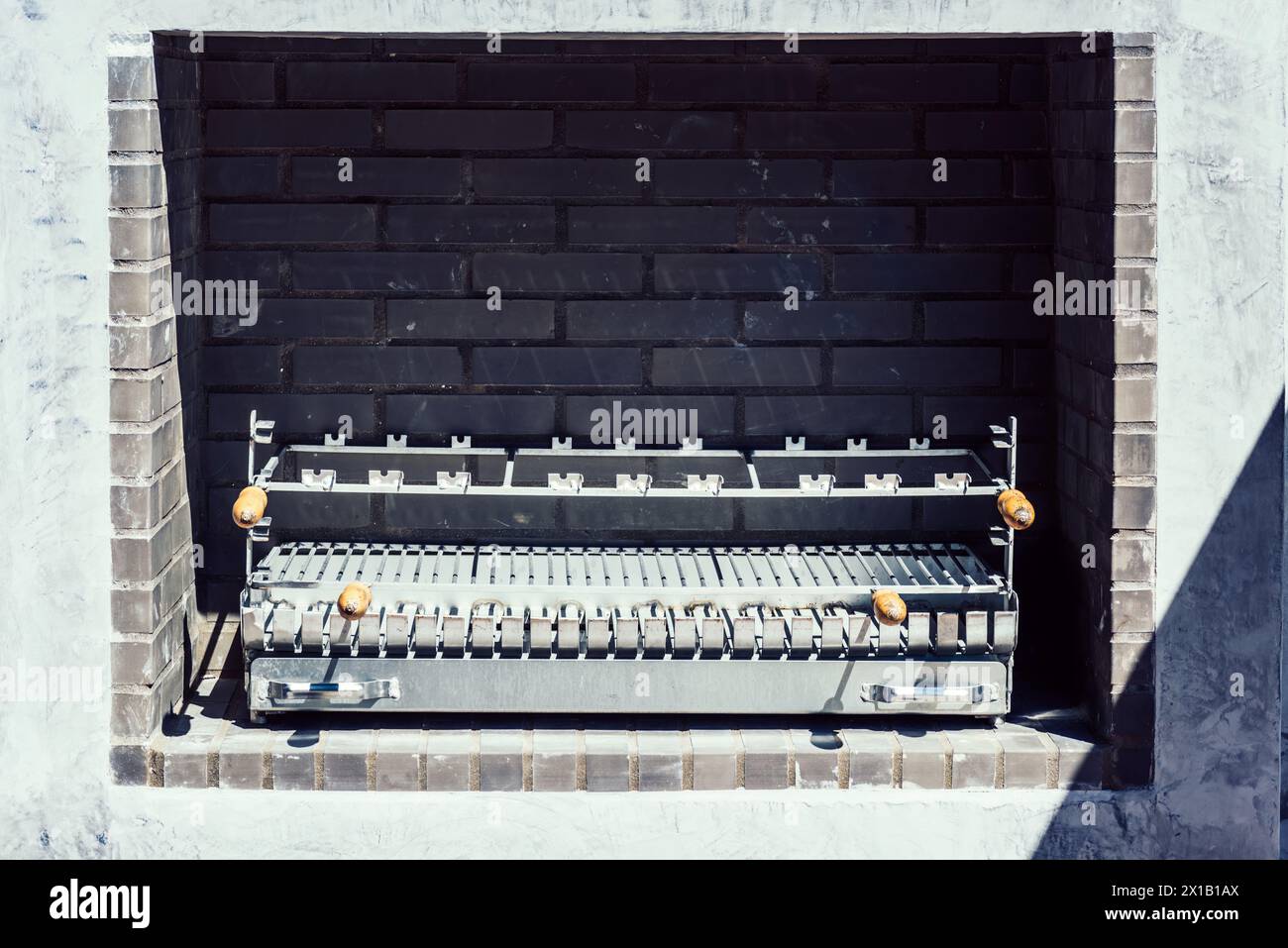 A traditional brick barbecue grill is set into a wall, featuring a ...