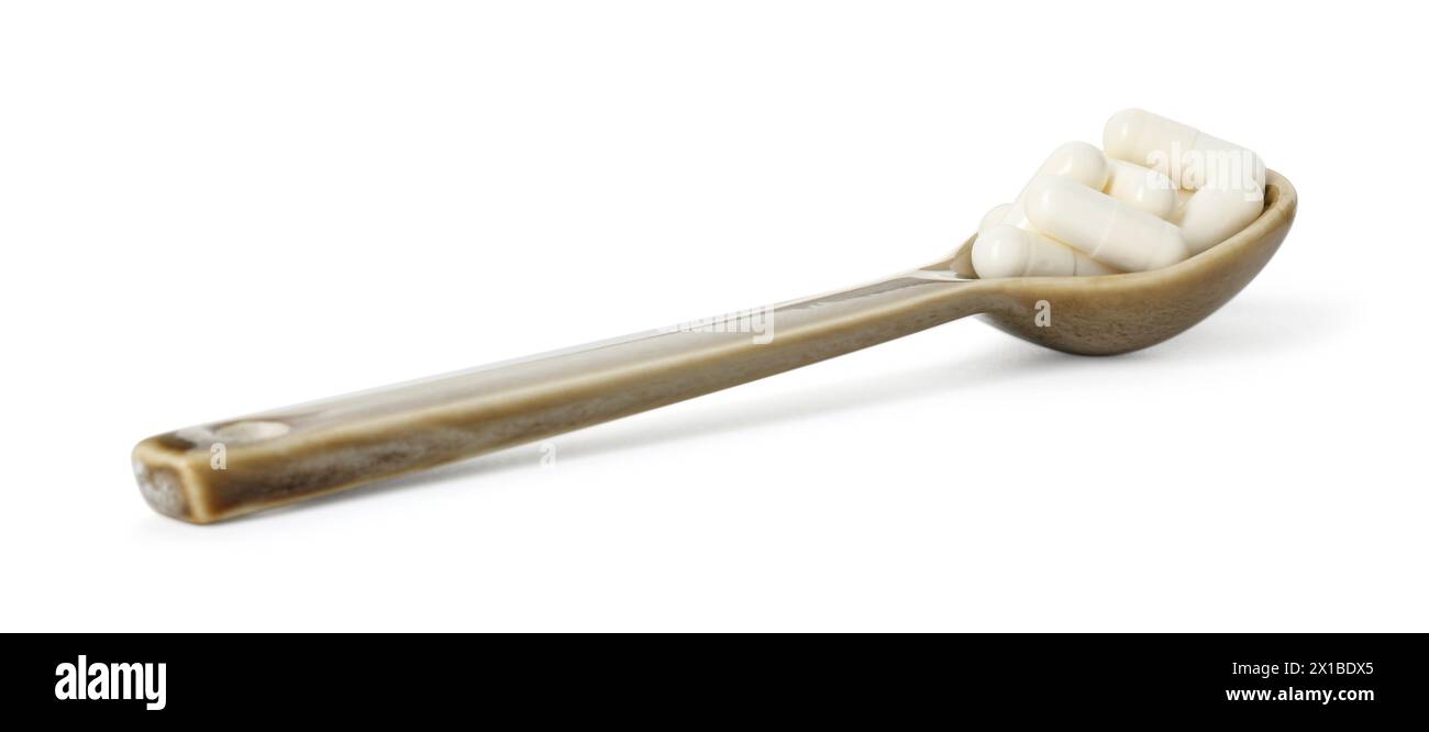 Vitamin capsules in spoon isolated on white. Health supplement Stock ...