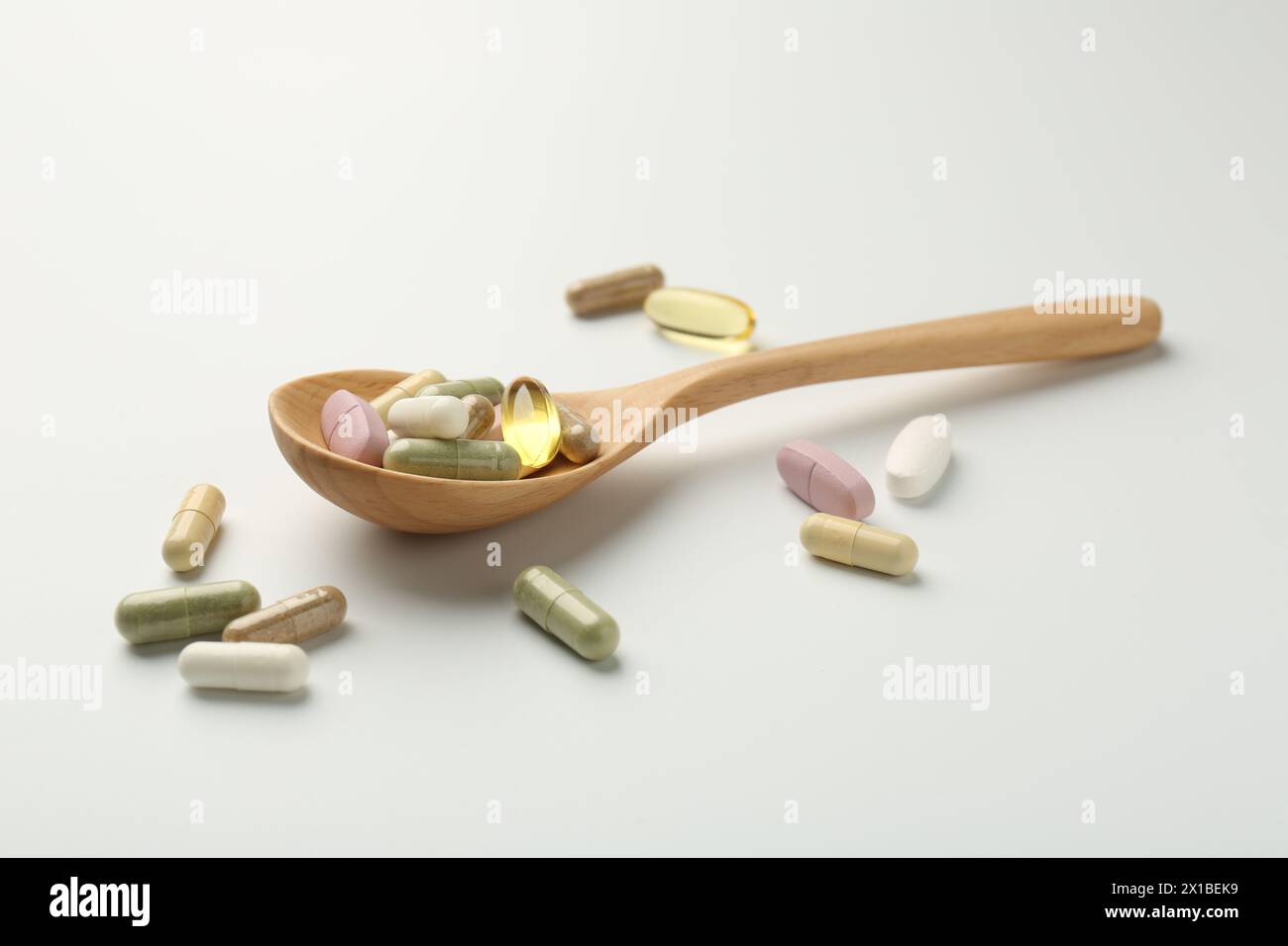 Different vitamin capsules in spoon on white background Stock Photo - Alamy