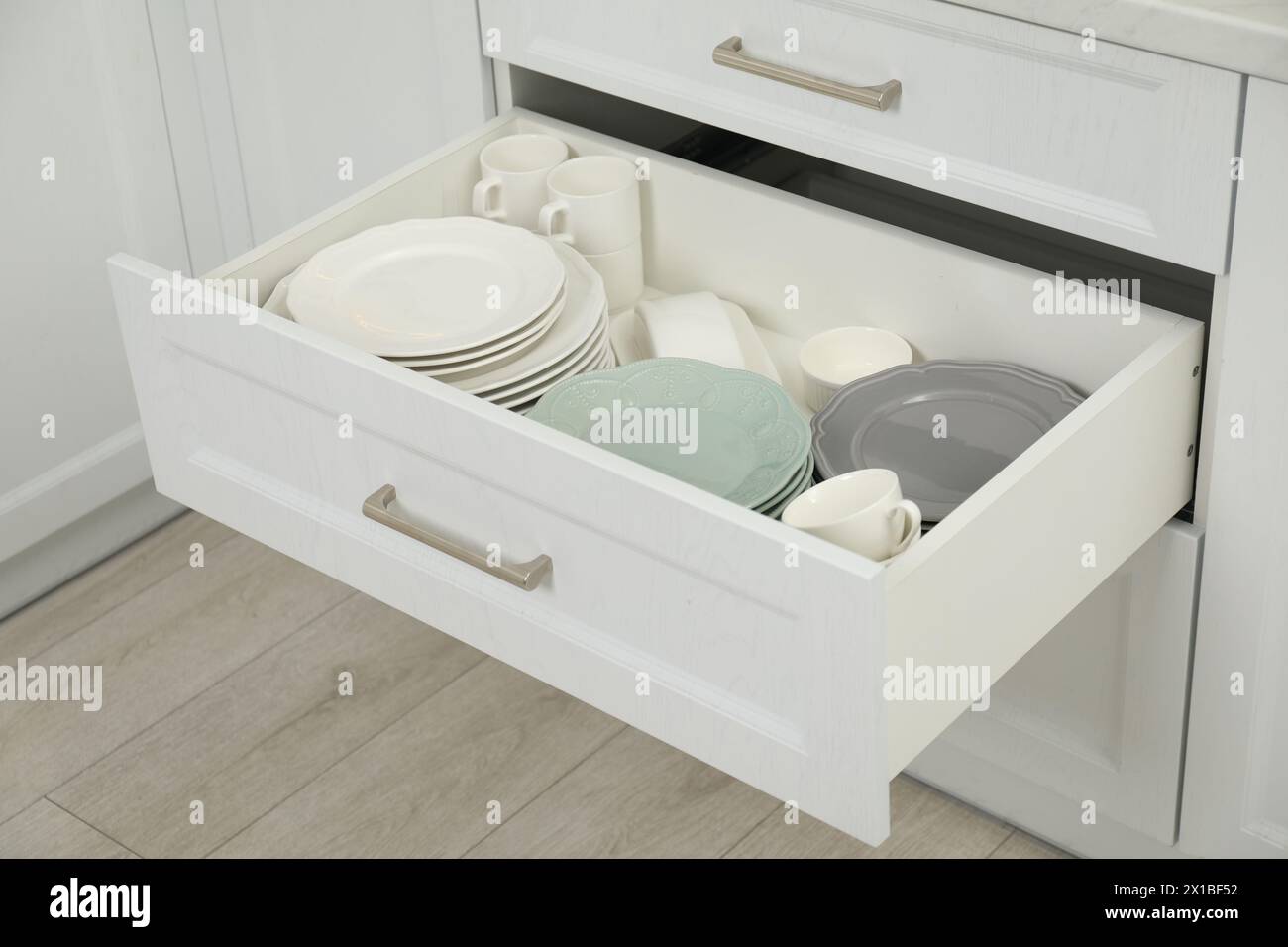 Clean plates, cups and bowl in drawer indoors Stock Photo - Alamy