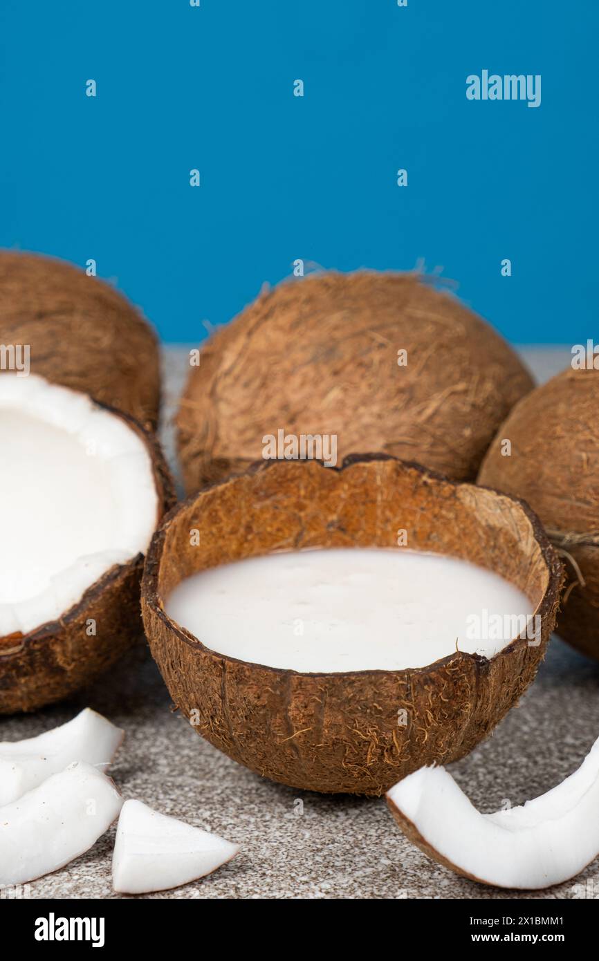 Coconut milk in coconut shell and half coconut, chopped flesh on a blue ...