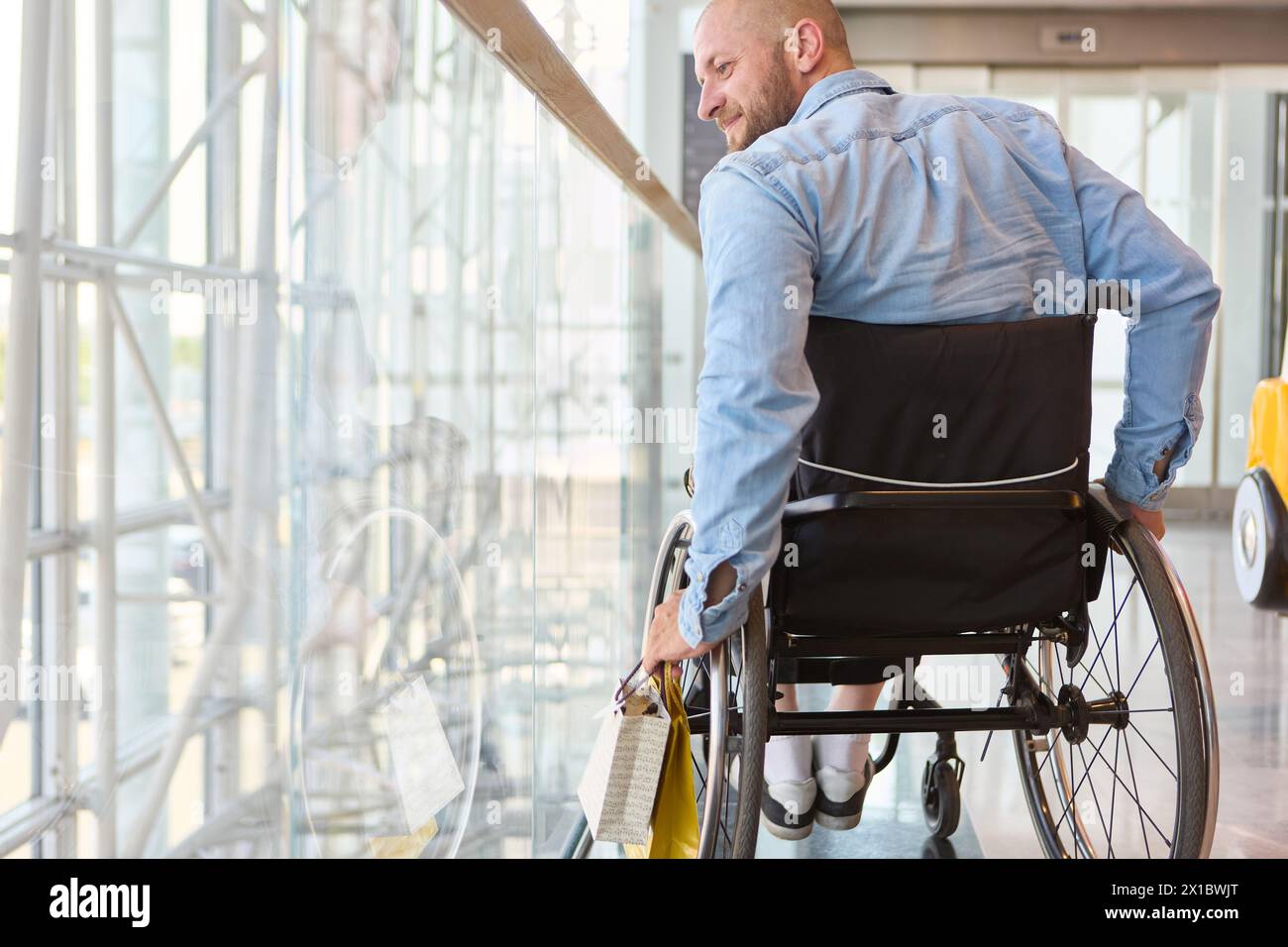 An adult man using a wheelchair is shown moving independently through a ...