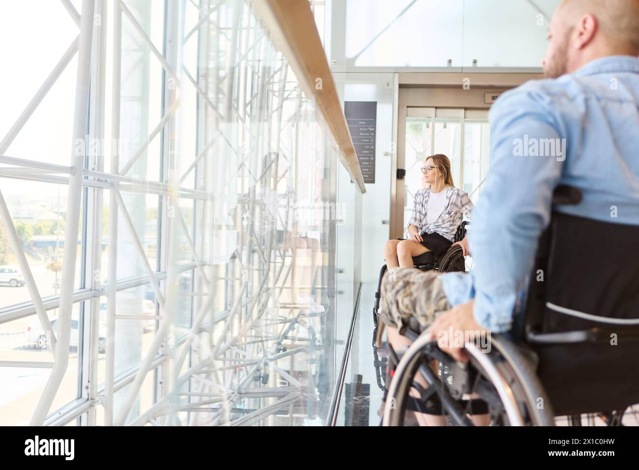 Two people who use wheelchairs appreciating a bright, airy space while ...