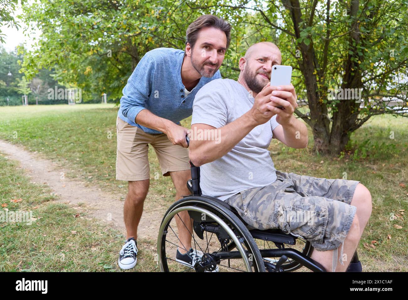 Two men sharing a moment, with one using a wheelchair, taking a selfie ...