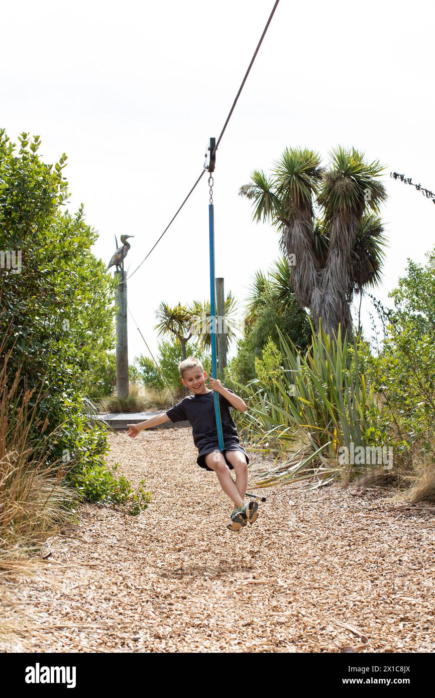 The boy is flying on a zip line in the park. A child is happily rocking ...