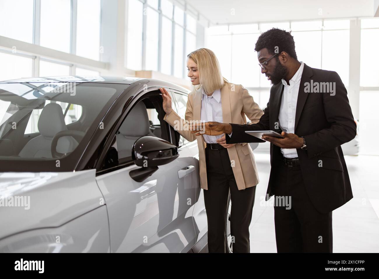 Successful businesswoman in car showroom sale of vehicles to customers ...