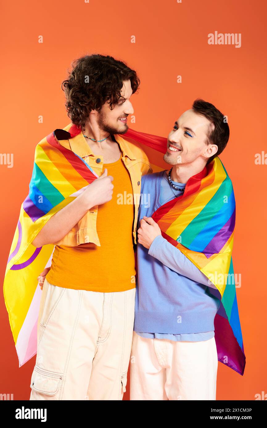 joyous appealing young gay men in cozy attires with rainbow flag on ...