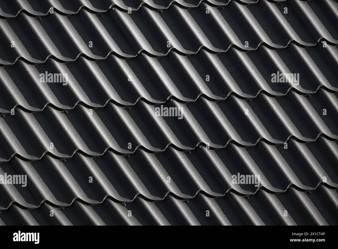 Black metal roof tiling with wavy shape pattern, close up black and ...