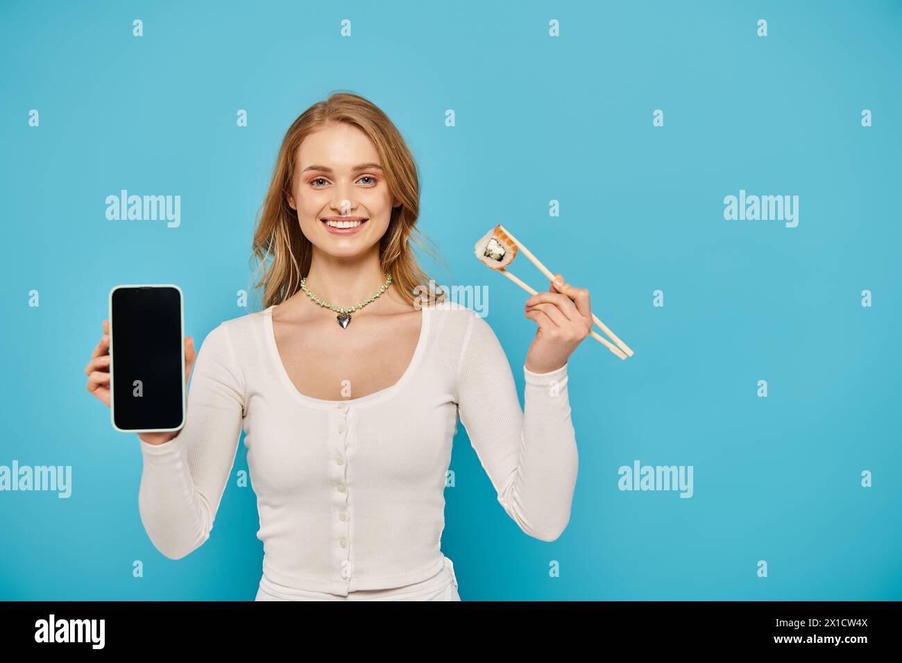 A woman balances a cell phone and chopsticks on blue backdrop Stock ...