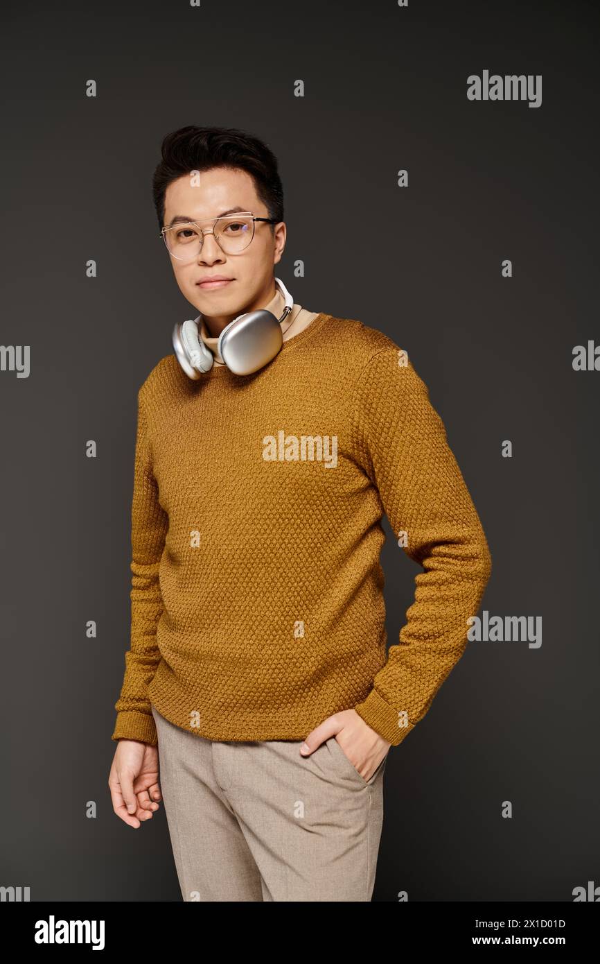A fashionable young man, wearing glasses and a sweater, strikes a pose ...