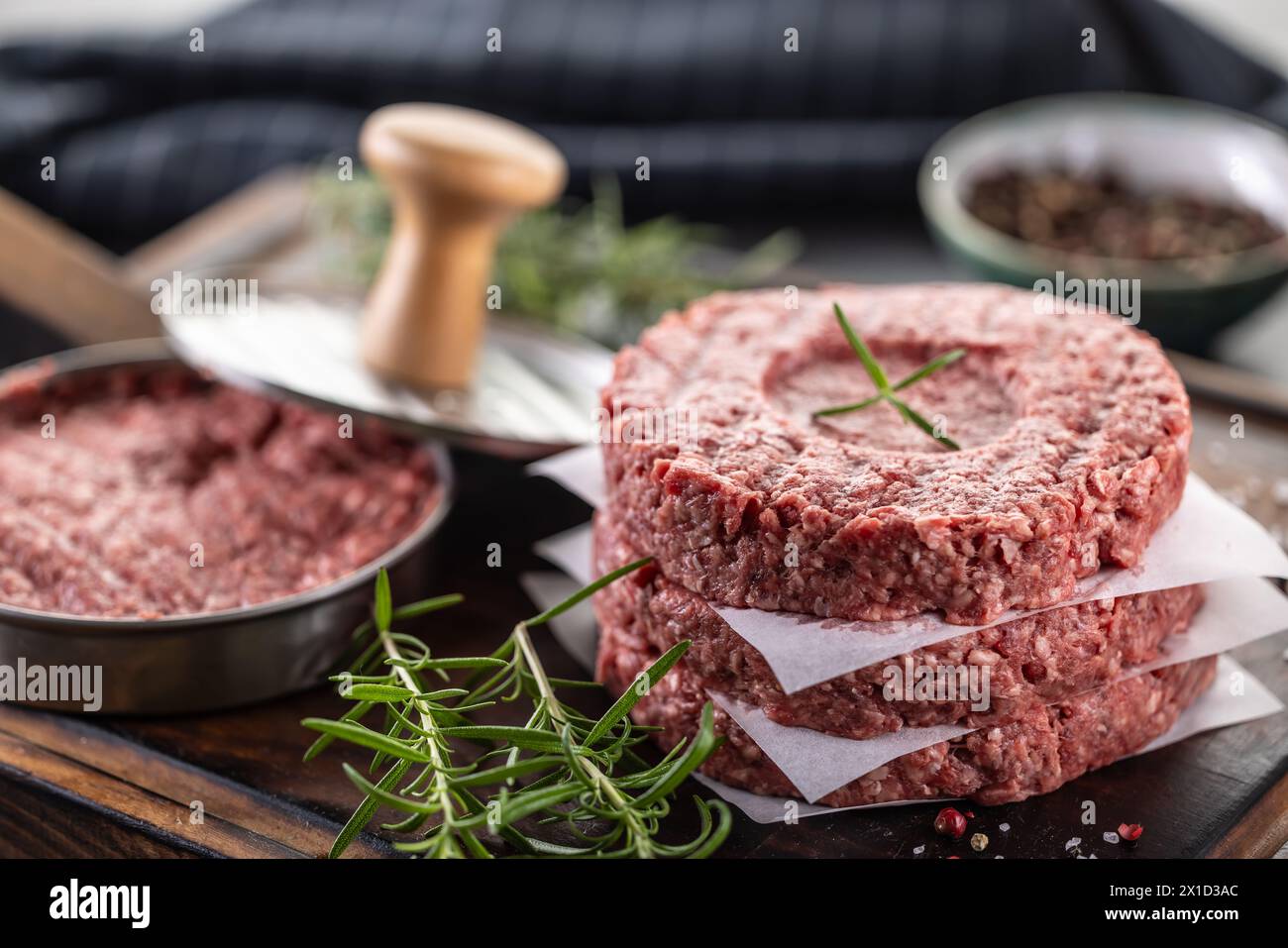 Fresh raw ground beef patties with rosemary salt and pepper made in a ...