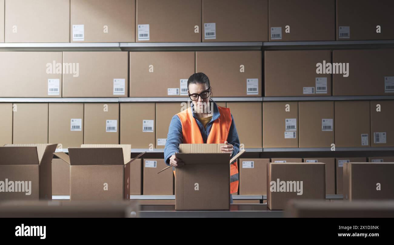 Bored woman working at the warehouse, she is closing the boxes on the ...