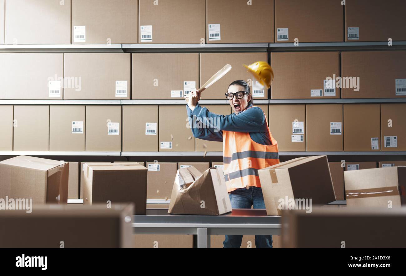 Angry aggressive warehouse worker hitting cardboard boxes with a bat ...