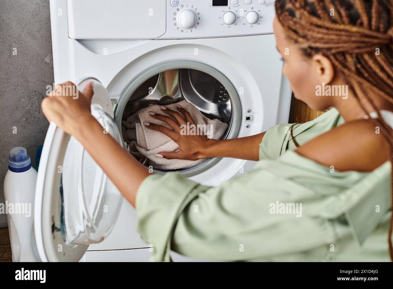 An African American woman with afro braids energetically doing laundry ...