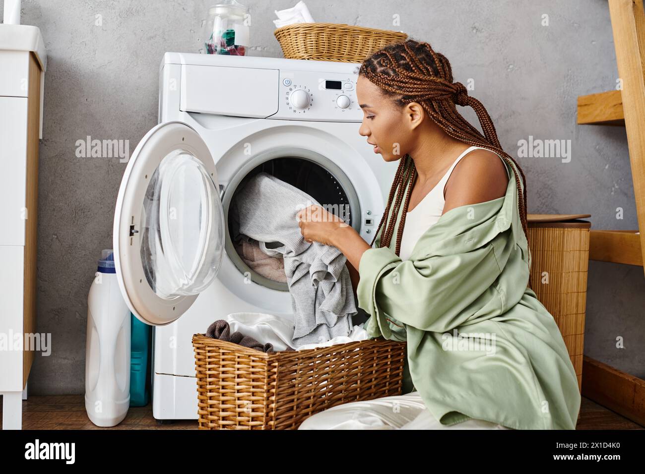 African American woman with afro braids sitting by a washing machine ...
