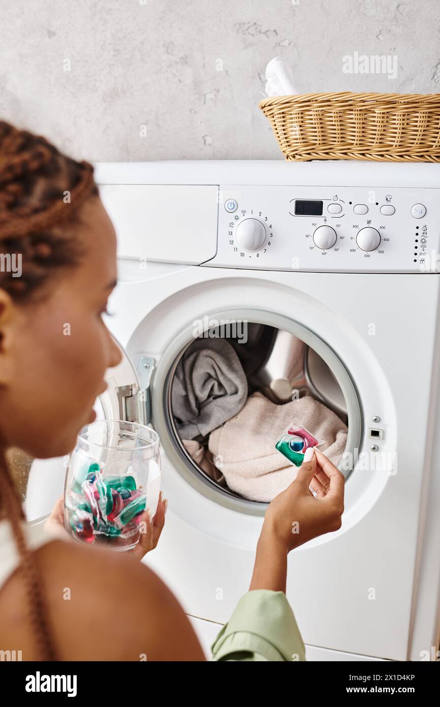 An African American woman with afro braids looks inside a washing ...
