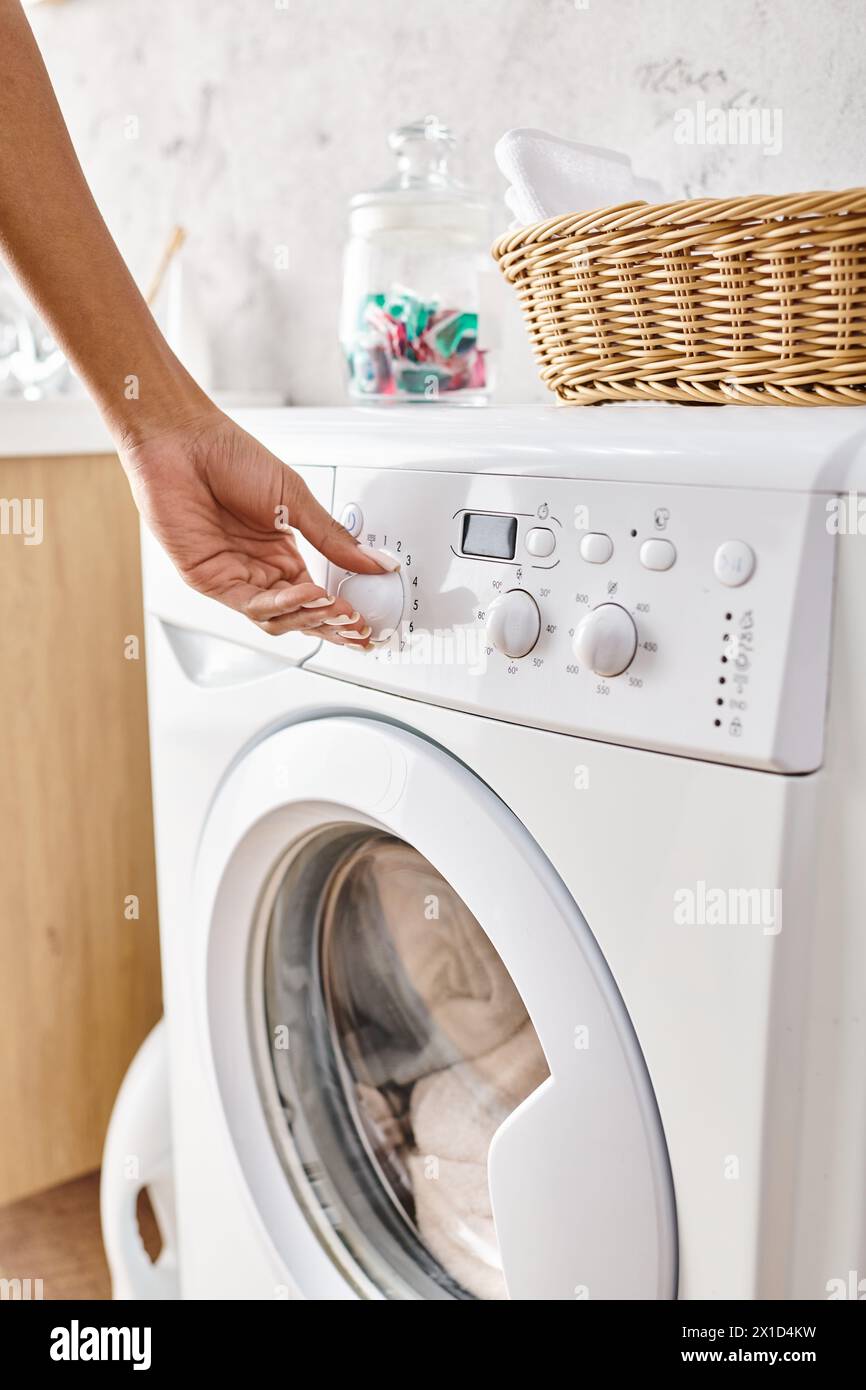 African American woman adjusting a button on a washing machine while ...