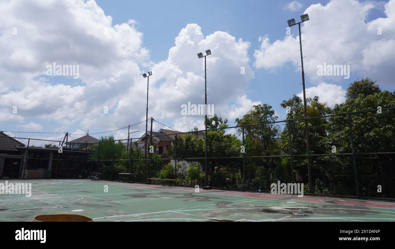A large outdoor basketball court with high court lights on a bright and ...