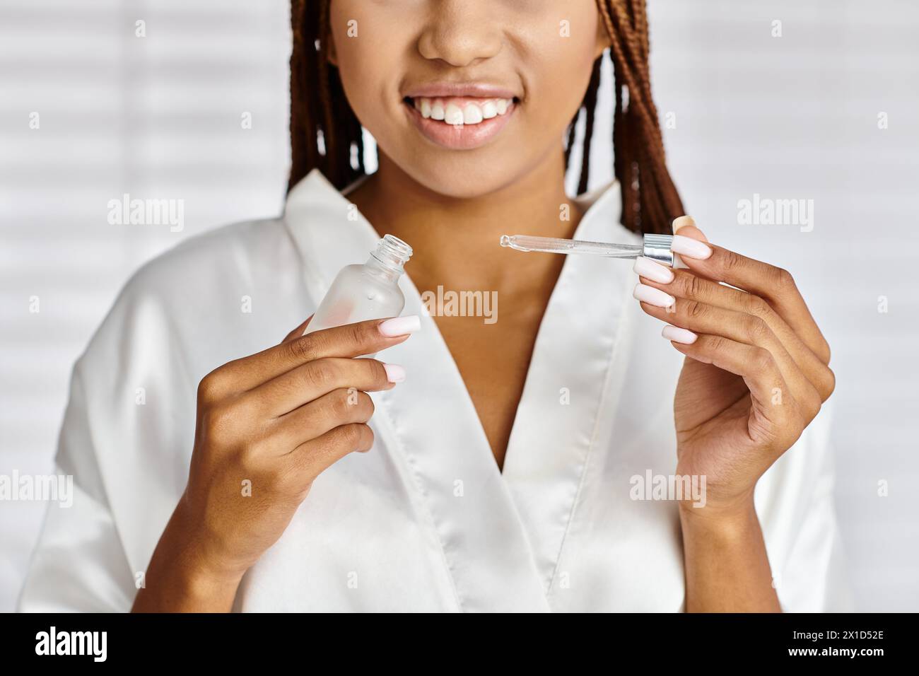 African American woman with afro braids holding a bottle with serum in ...