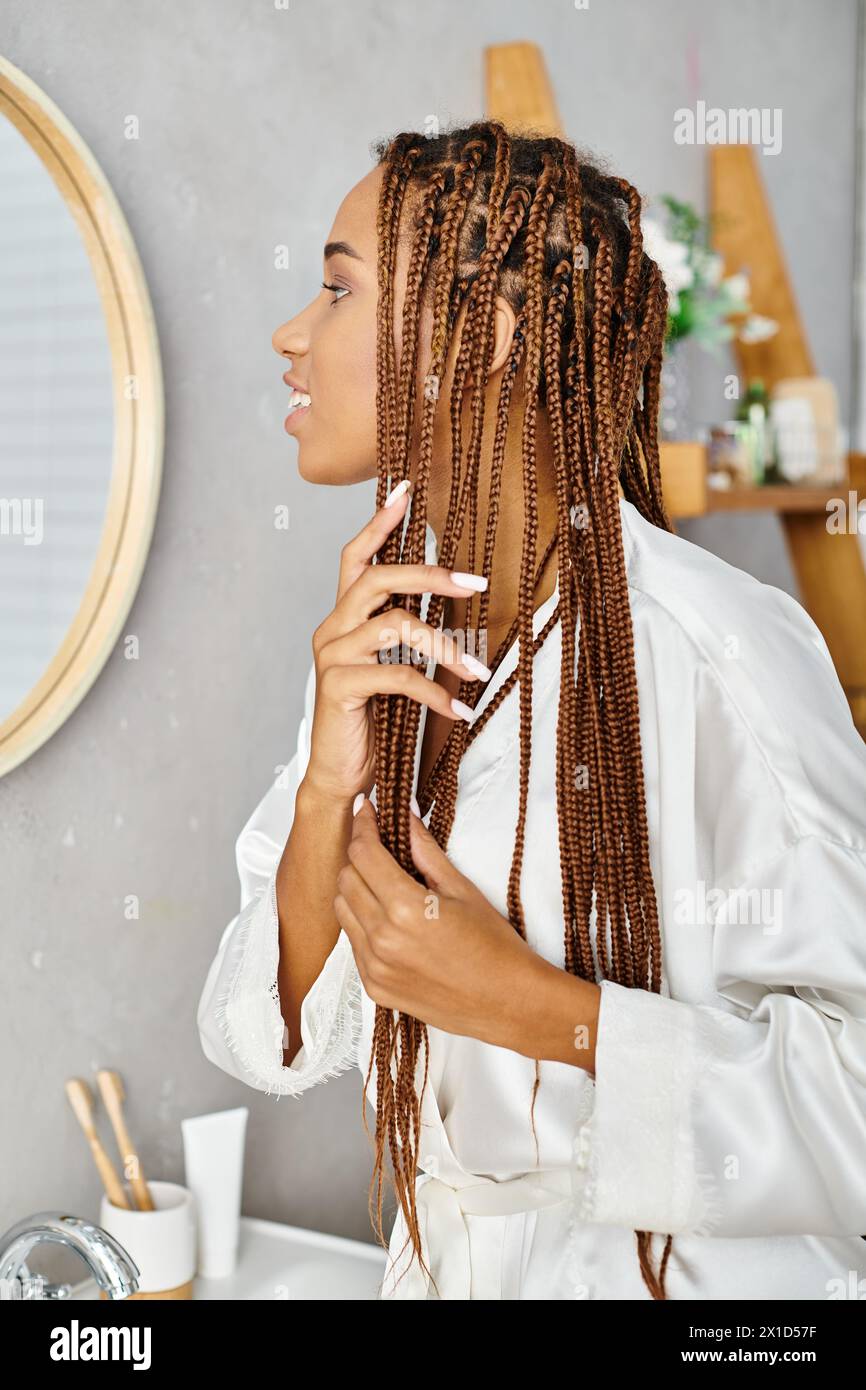 An African American woman with afro braids brushing her hair in a ...