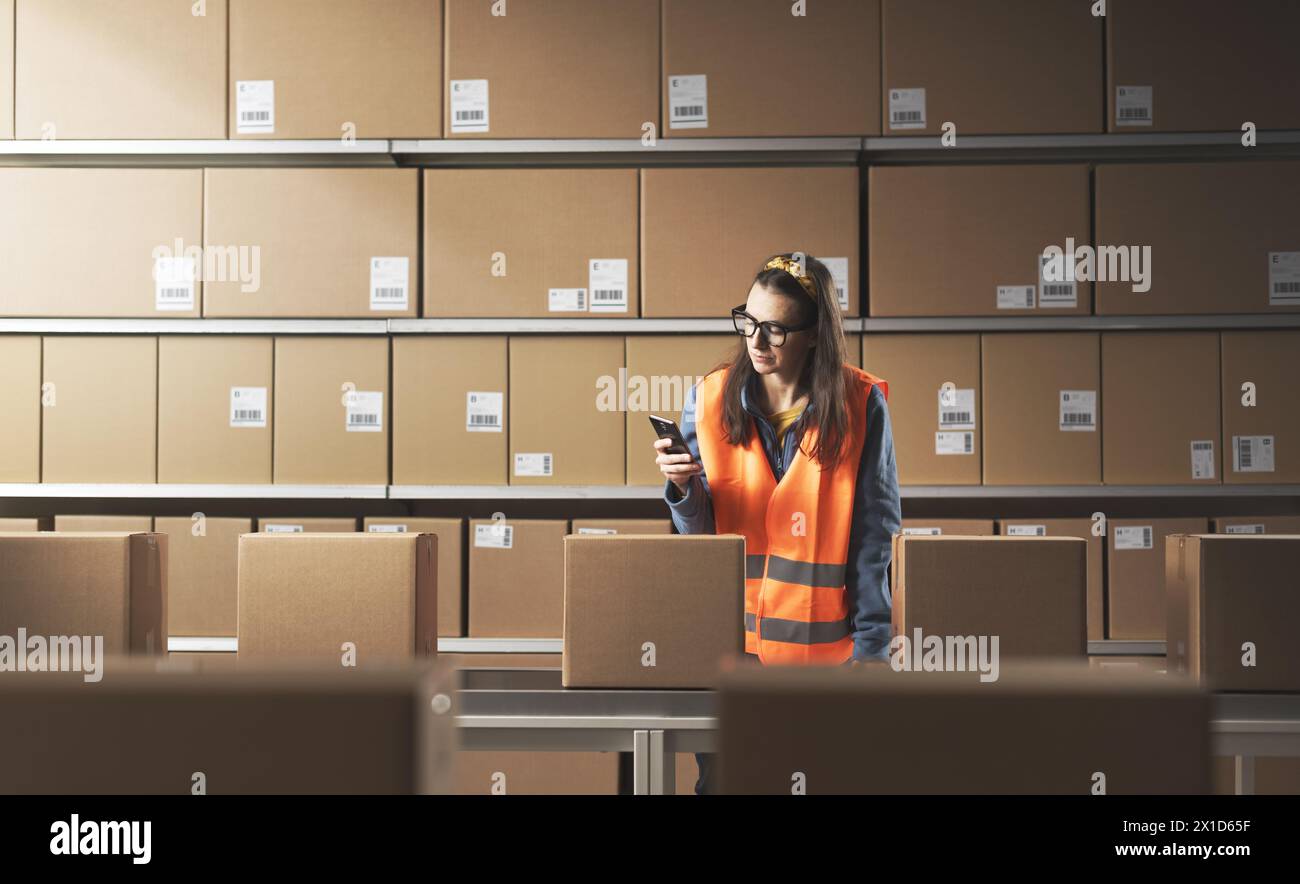Bored distracted female warehouse worker using her smartphone at work ...