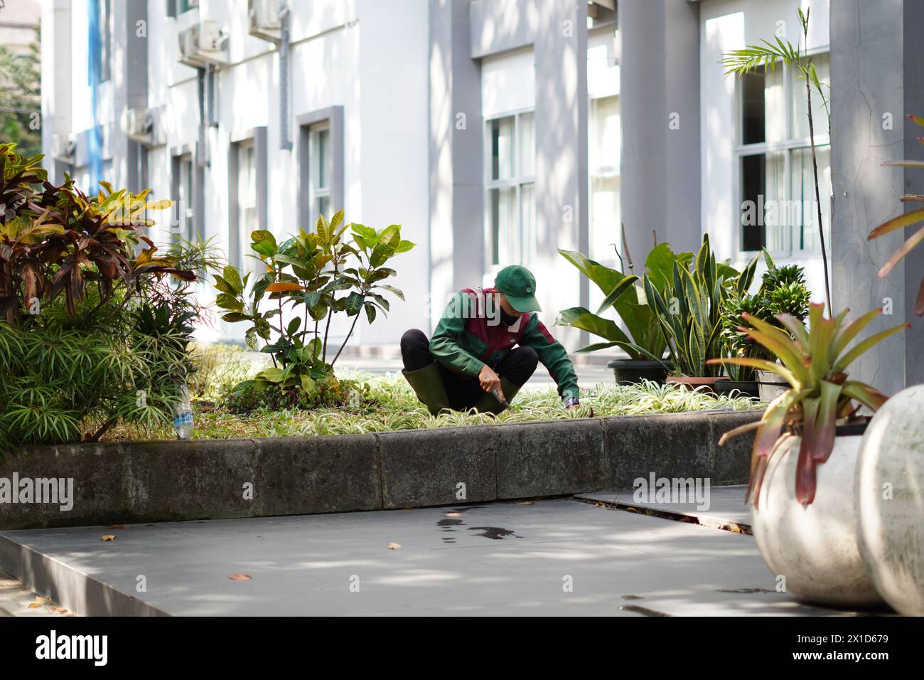 Garden workers in green clothes cleaning the garden in front of the ...