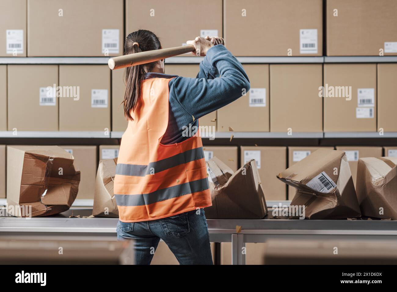 Angry rebellious warehouse worker smashing boxes on the conveyor belt ...