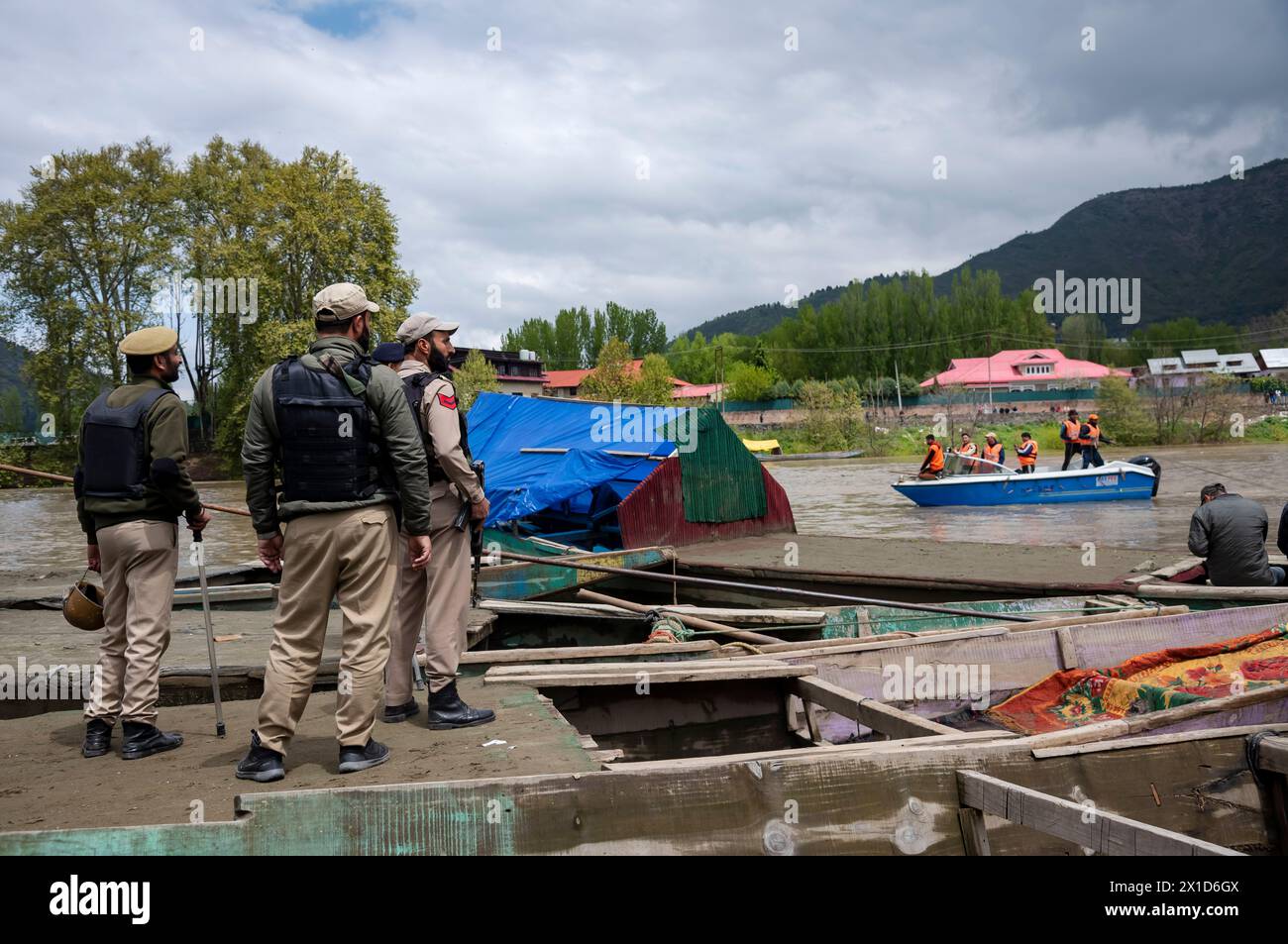 Indian Policemen stand on a boat past State Disaster Response Force (SDRF) conducting a search ...