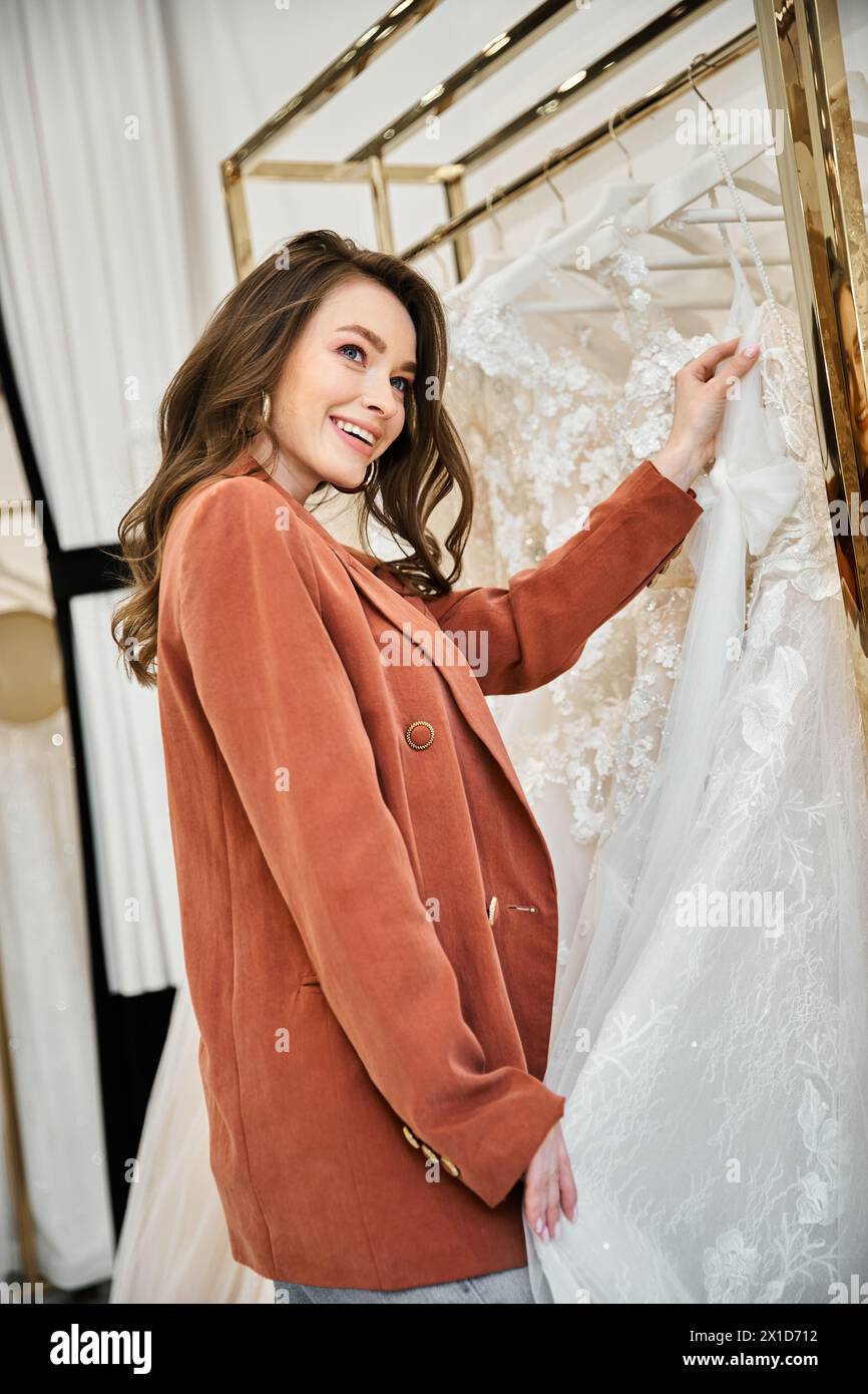 A young beautiful bride is standing next to a rack of dresses ...