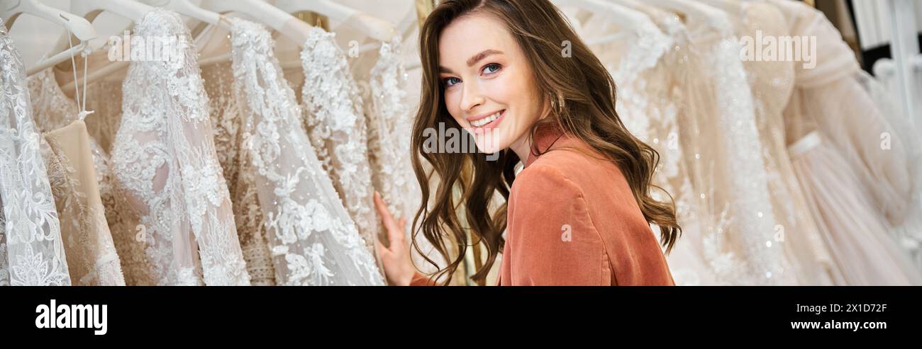 A young bride stands before a selection of wedding dresses, trying to ...
