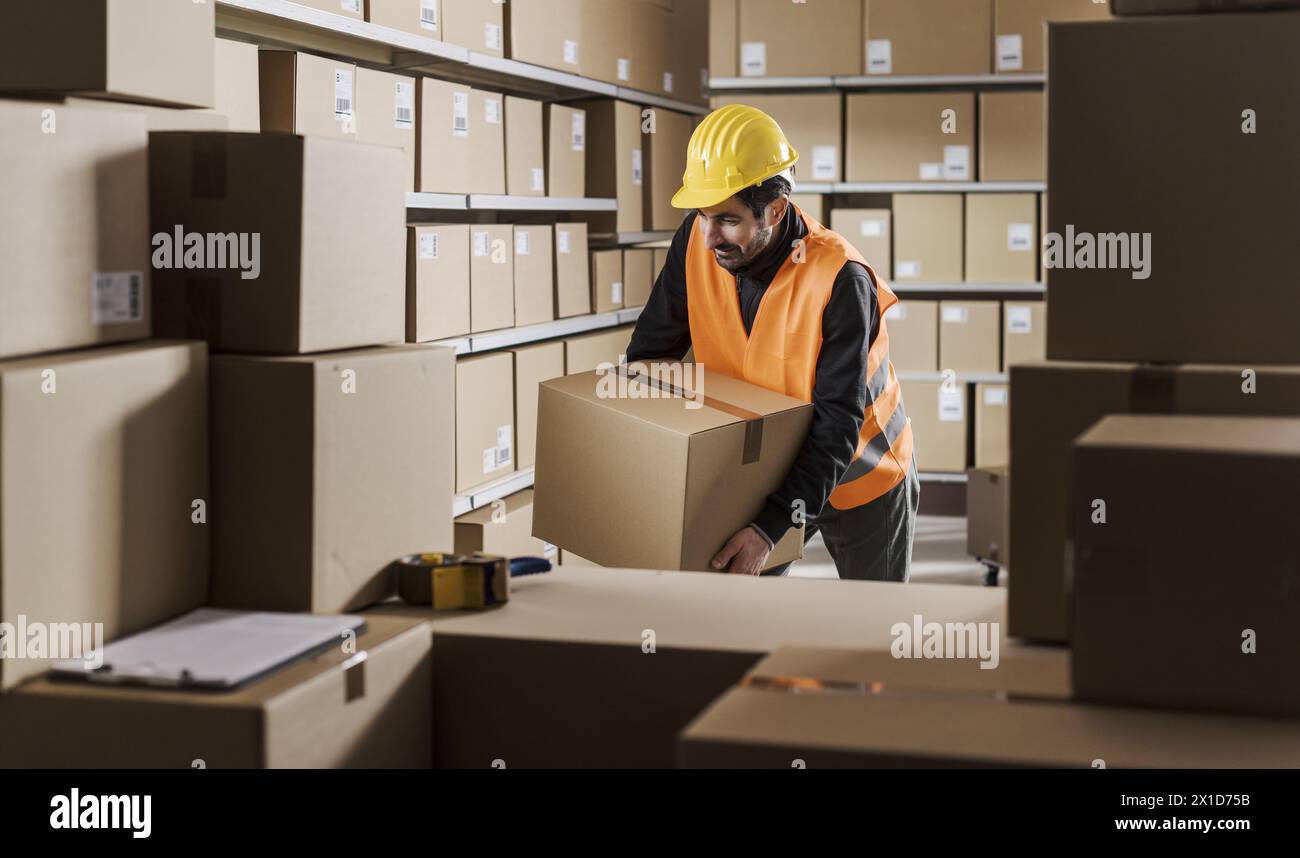 Tired warehouse worker having a bad back pain at work, he is lifting a ...