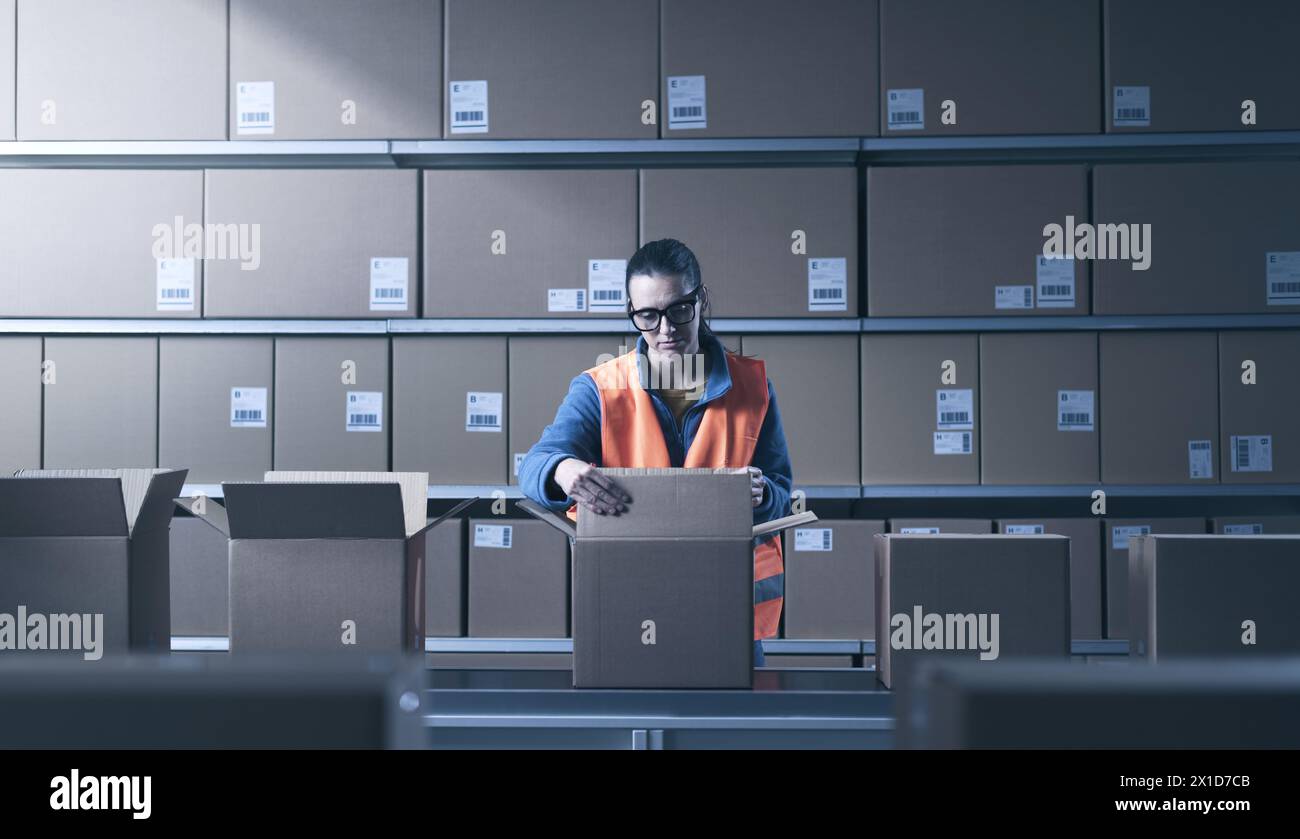 Bored woman working at the warehouse, she is closing the boxes on the ...