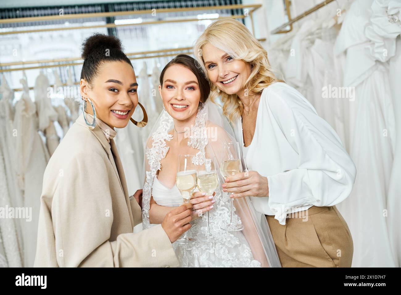 Young bride, middle-aged mother, and bridesmaid in bridal salon, stand ...