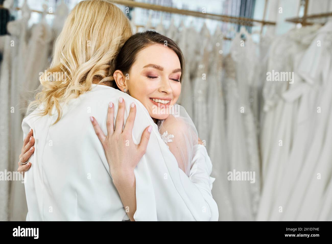 A young bride in a wedding dress hugs her middle-aged mother in a ...