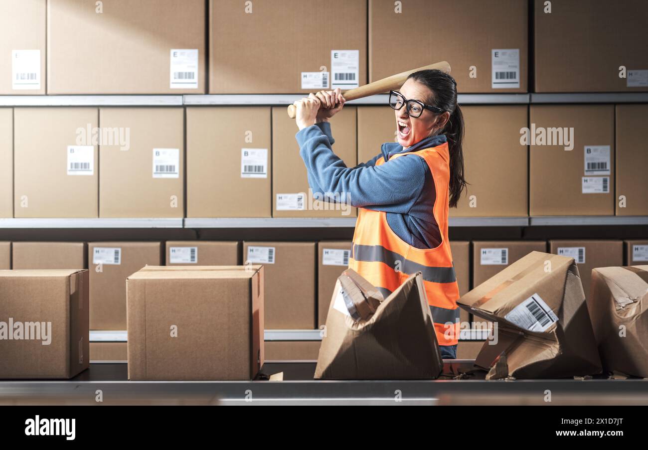 Aggressive rebellious warehouse worker smashing boxes at work, she is ...