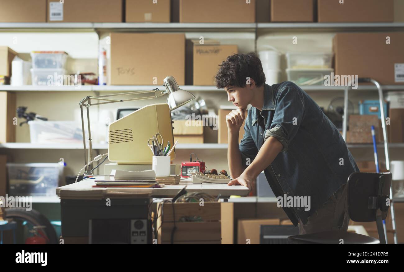 Smart nerd adolescent in the garage, he is working with an old computer: creativity and ...