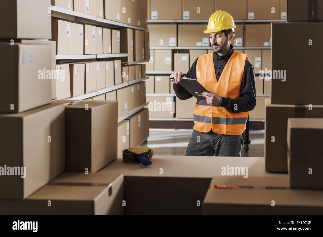 Warehouse worker holding a clipboard and checking boxes, logistics and ...