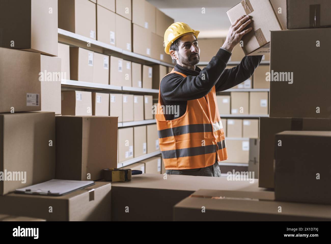 Warehouse clerk stacking cardboard boxes and checking orders: logistics ...