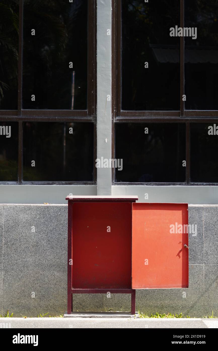 An open red iron box with a black window and gray walls as a background ...